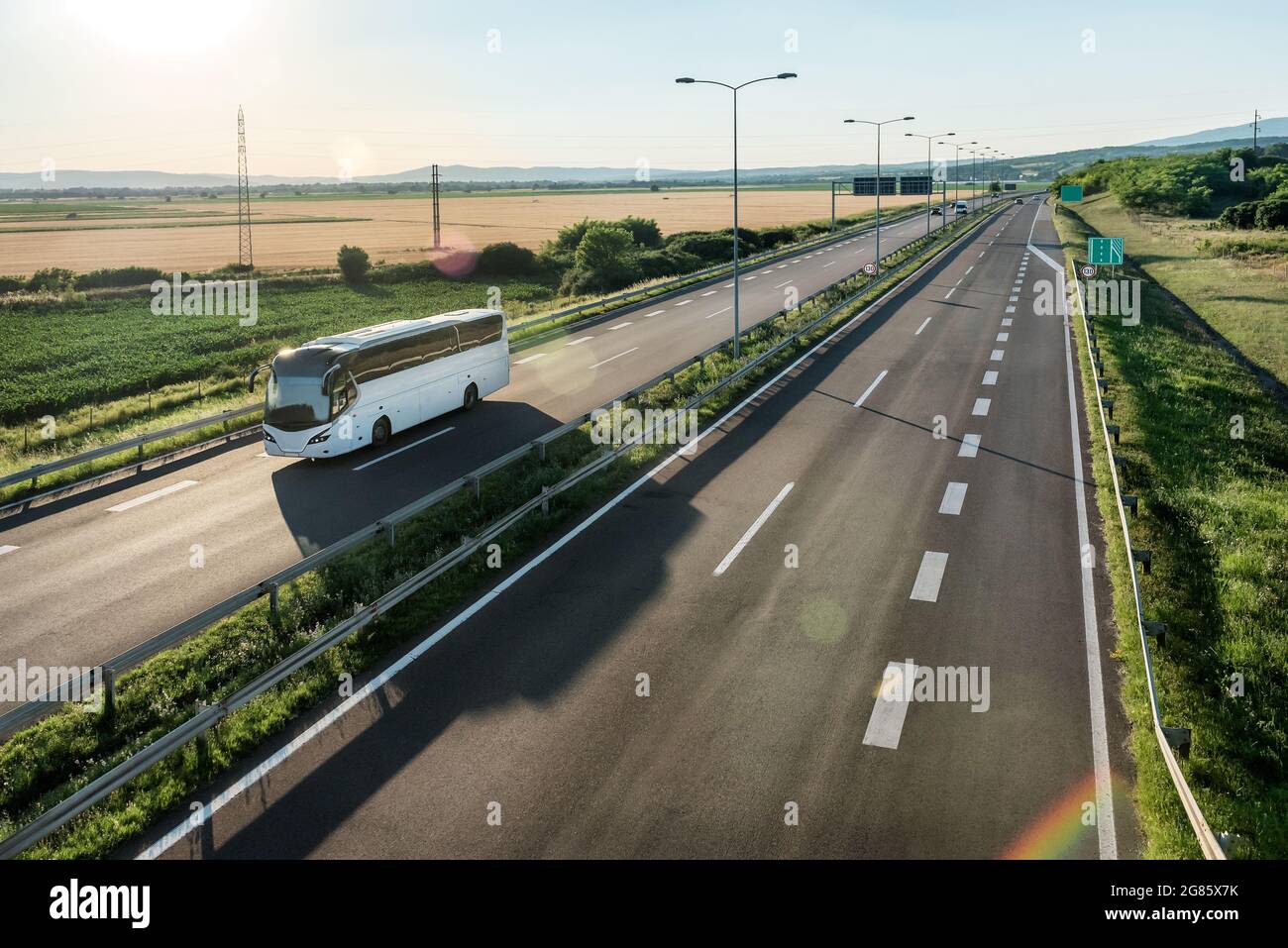 Modern White bus traveling on a wide highway in a rural backdrop ...