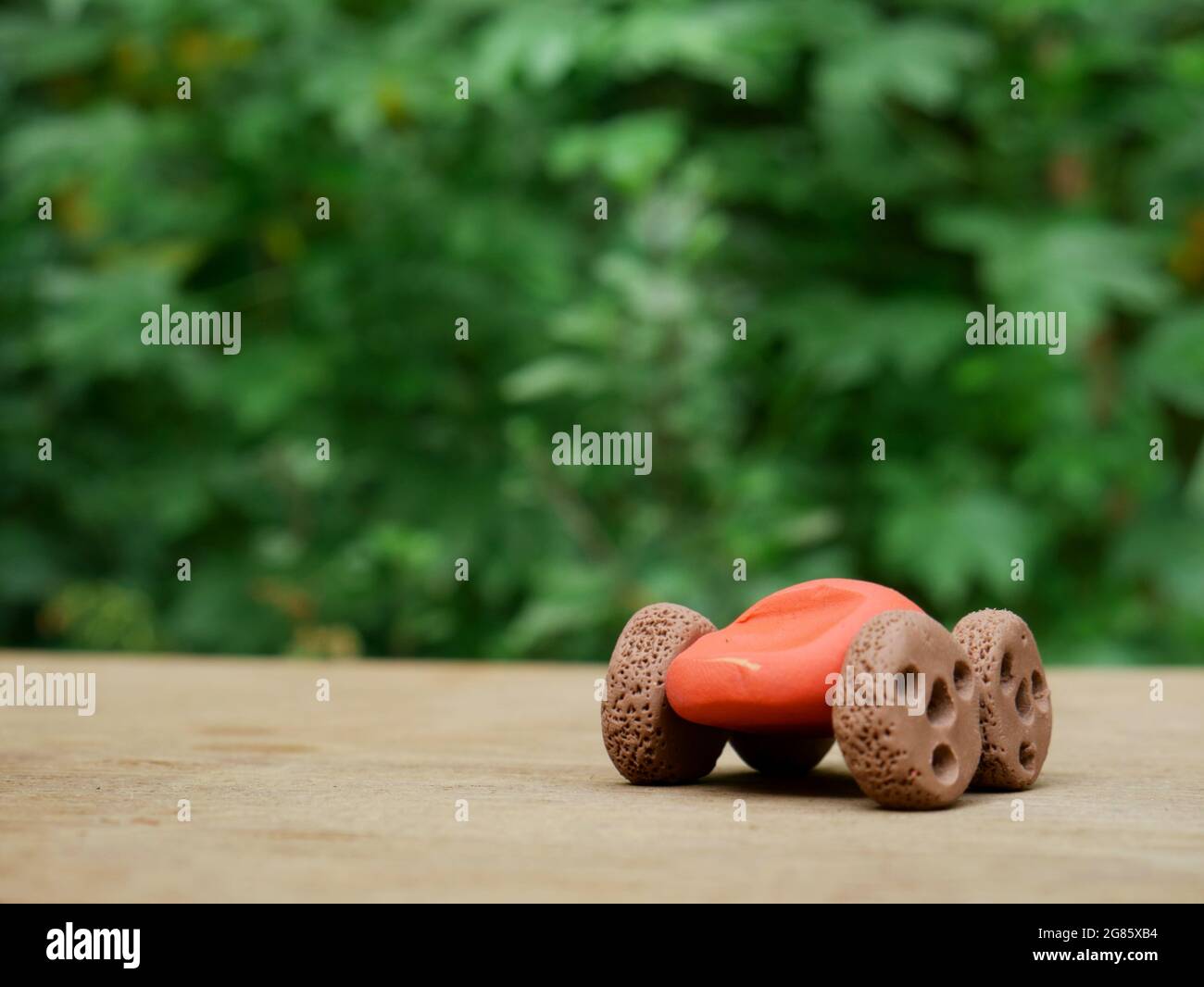 hand made clay art car presented on stone surface at natural green blur ...