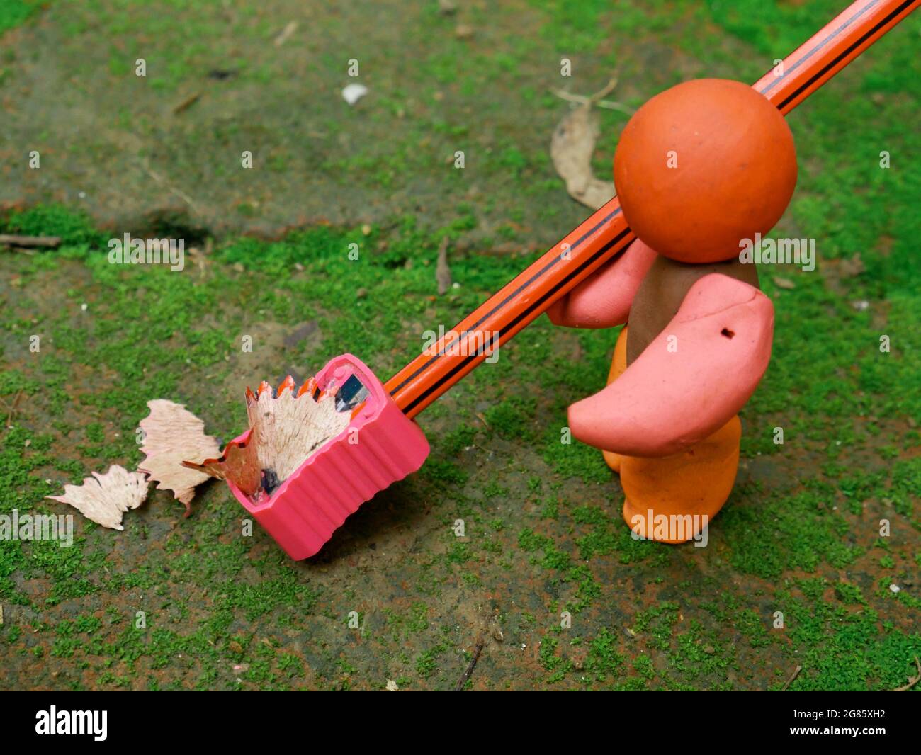 Soft clay toy man sharping pencil from sharpener at green natural field ...