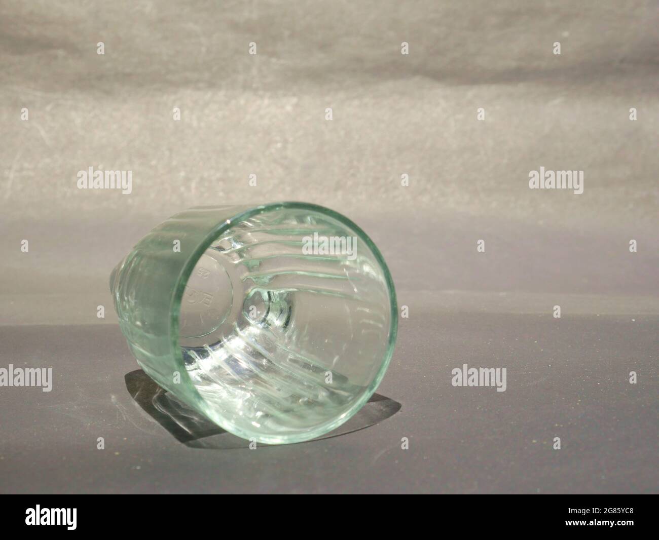 Empty Water glass fallen down on gray backdrop on day light, kitchen cutlery product image Stock ...