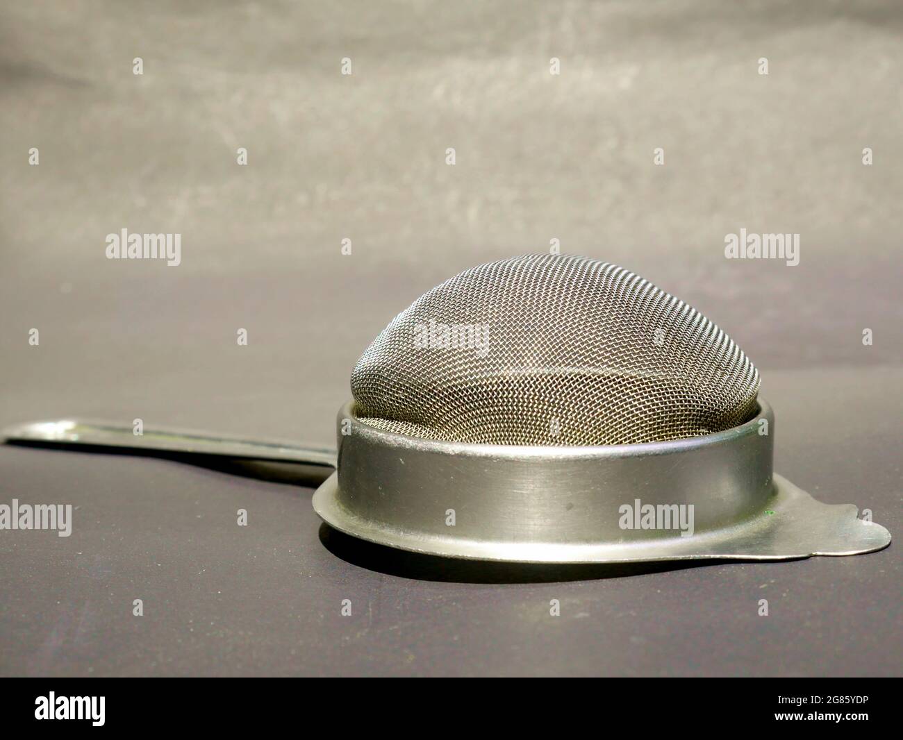 Stainless steel tea filter isolated on gray backdrop, kitchen cutlery ...