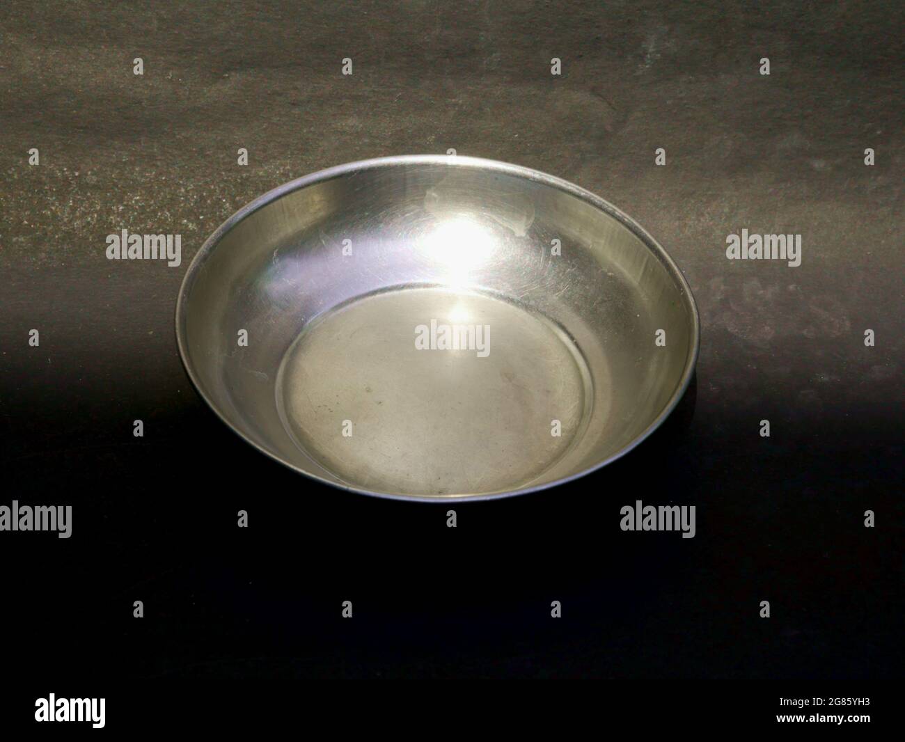 Stainless steel food plate displayed on gray backdrop, kitchen cutlery ...