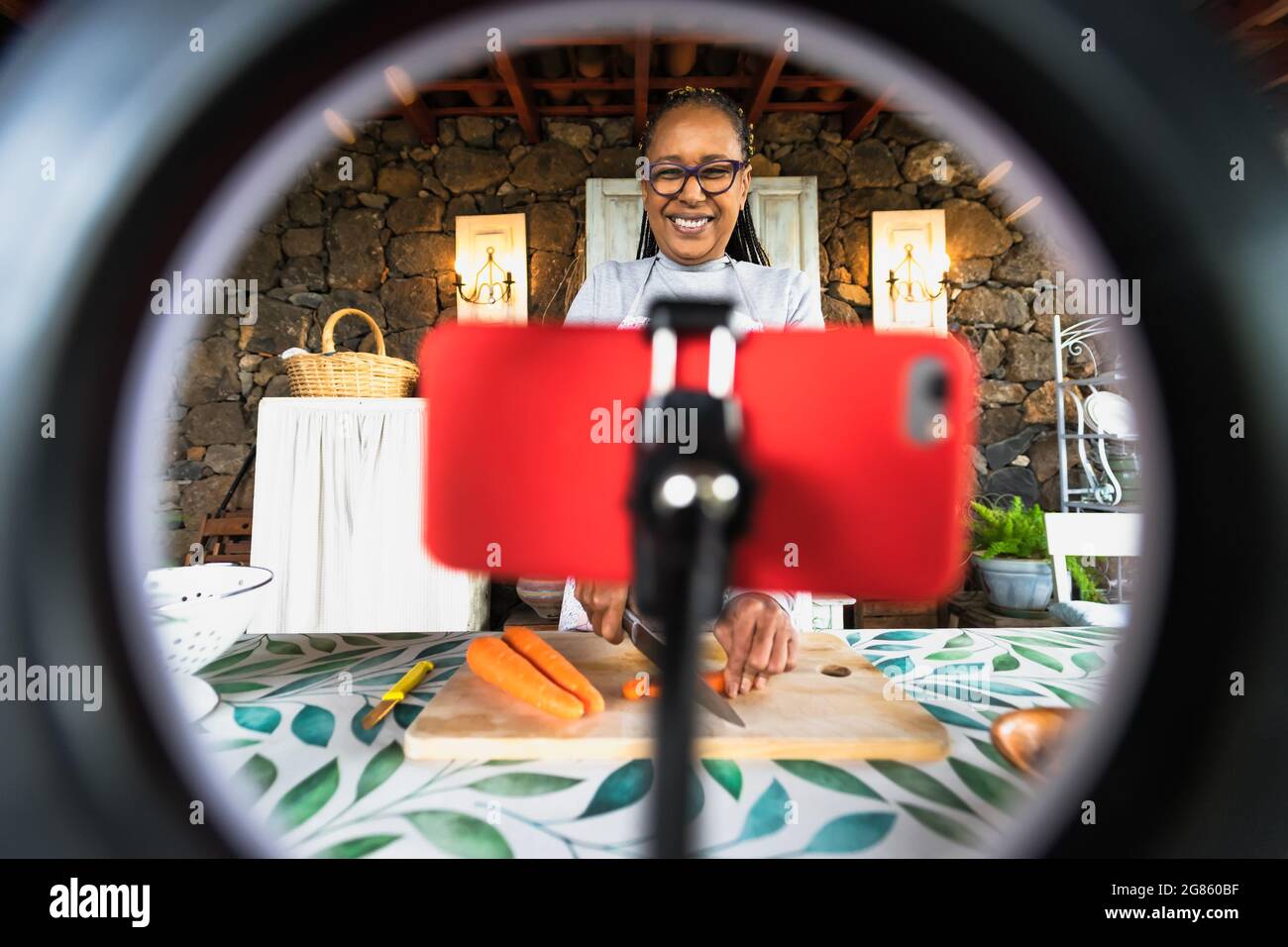 Happy Afro senior woman preparing food recipe while streaming online ...