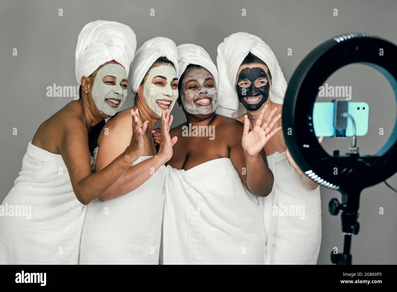 Happy multiracial females having skin care spa day while streaming on ...