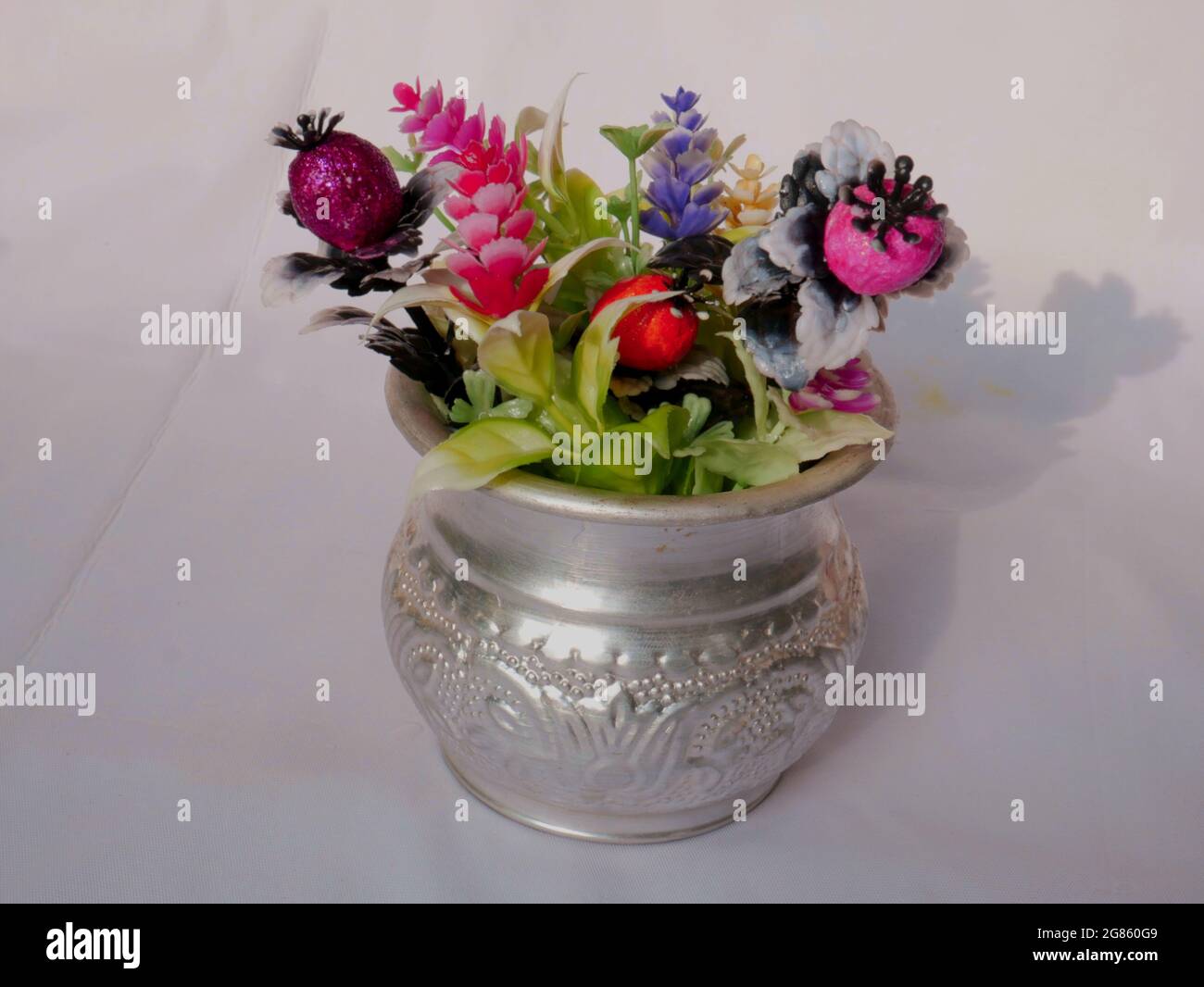 Artificial flower presented on silver metal pot at white background ...