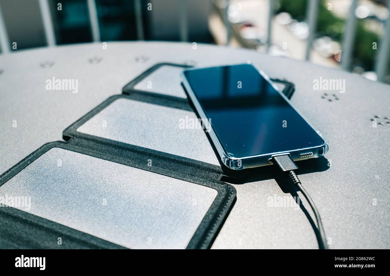 Charging a smartphone from home with a portable solar panel charger ...