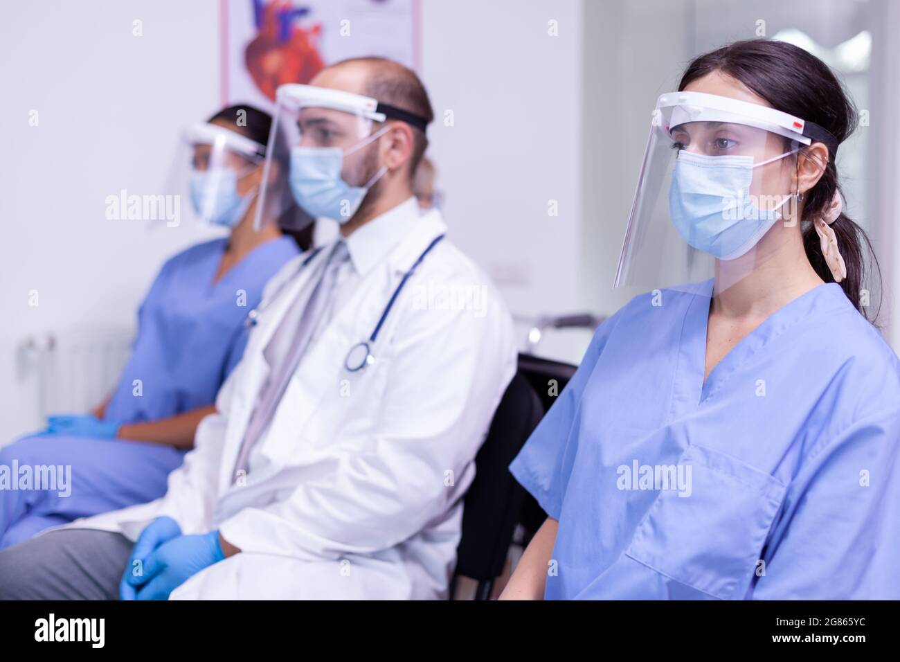 Portrait of medical staff in uniform and protective mask looking at ...
