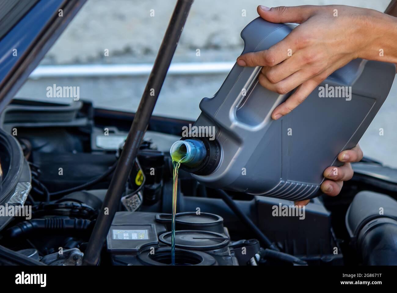 An auto mechanic changing oil pours oil into a car engine. Selective ...