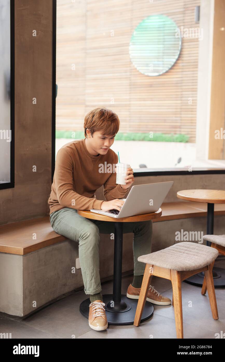 Handsome man sitting alone at table in coffee shop cafe working Stock ...