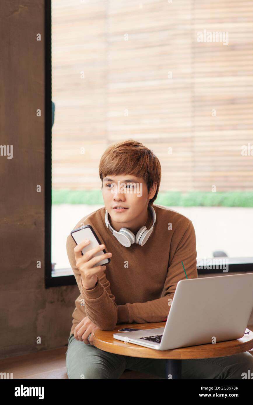 Smiling young man using gadgets at coffee shop Stock Photo - Alamy