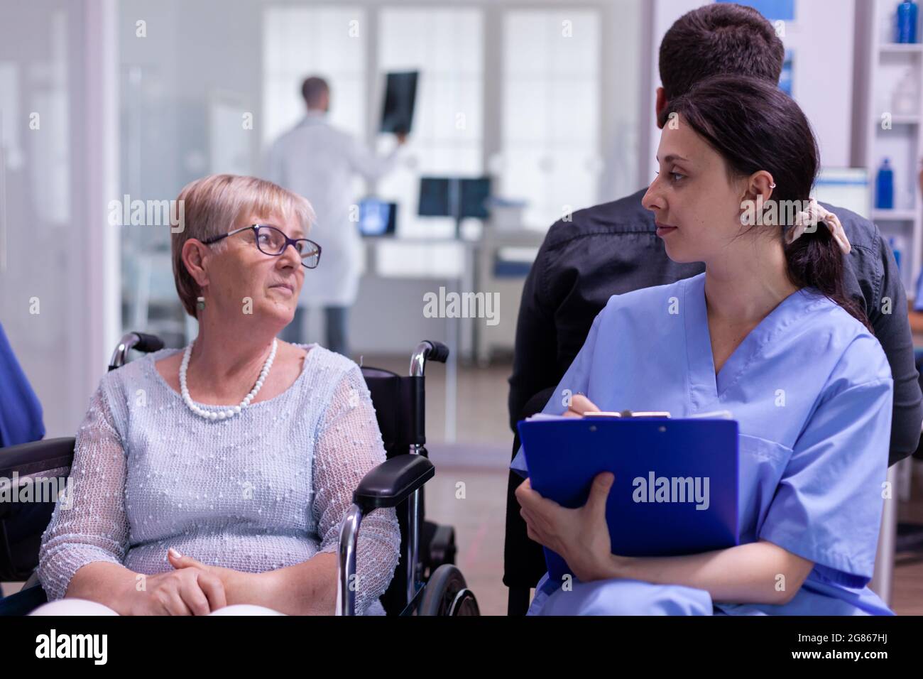Medical nurse explaining diagnosis to handicapped senior woman patient ...