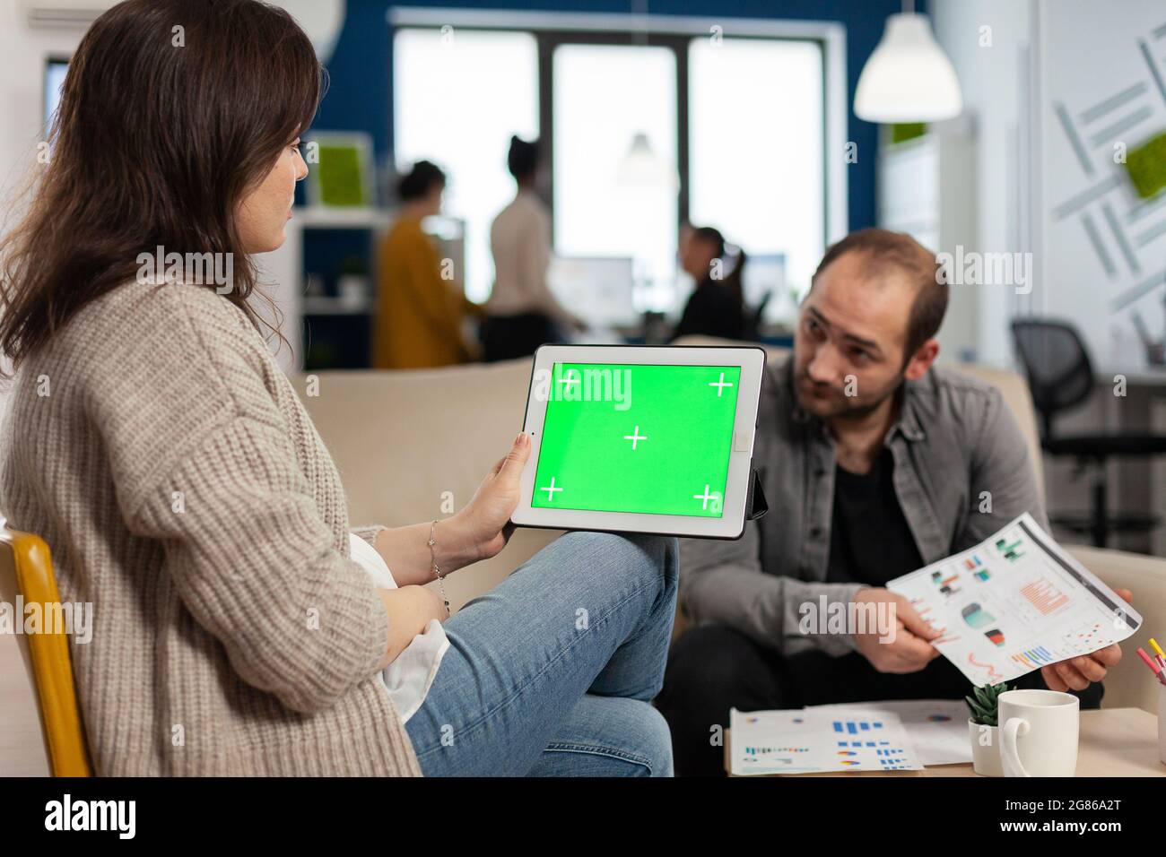 Over the sholder of manager woman sitting on couch talking with ...