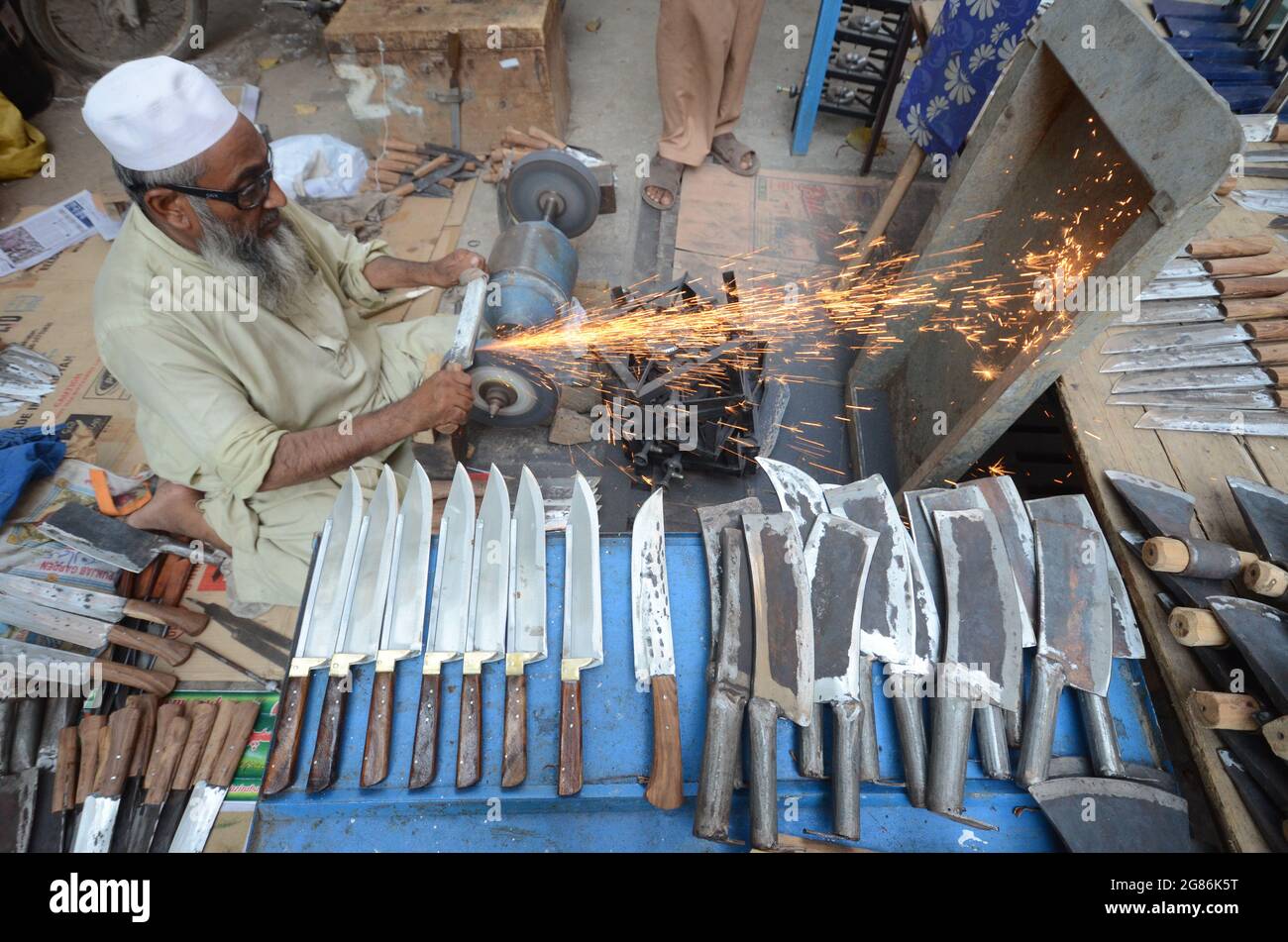 Peshawar, Pakistan. 17th July, 2021. A Pakistani vendor sharpen axe ...