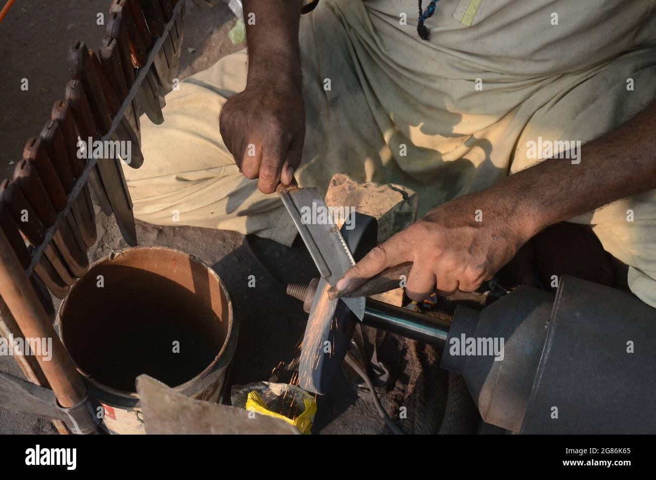 Peshawar, Pakistan. 17th July, 2021. A Pakistani vendor sharpen axe ...