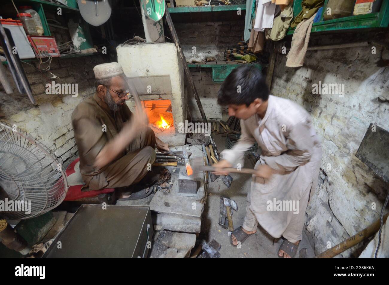 Peshawar, Pakistan. 17th July, 2021. A Pakistani vendor sharpen axe ...