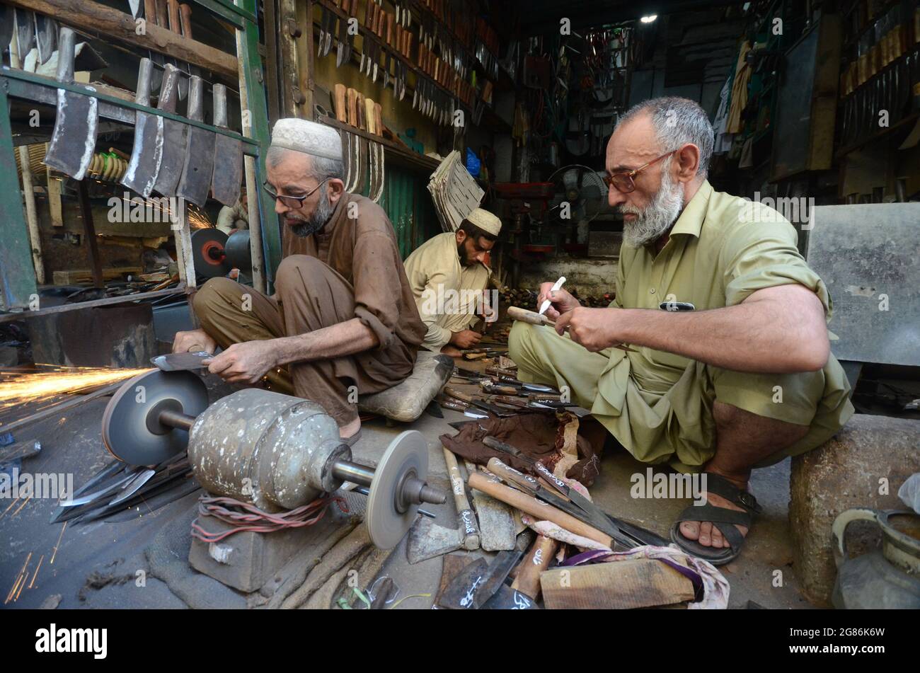 Peshawar, Pakistan. 17th July, 2021. A Pakistani vendor sharpen axe ...