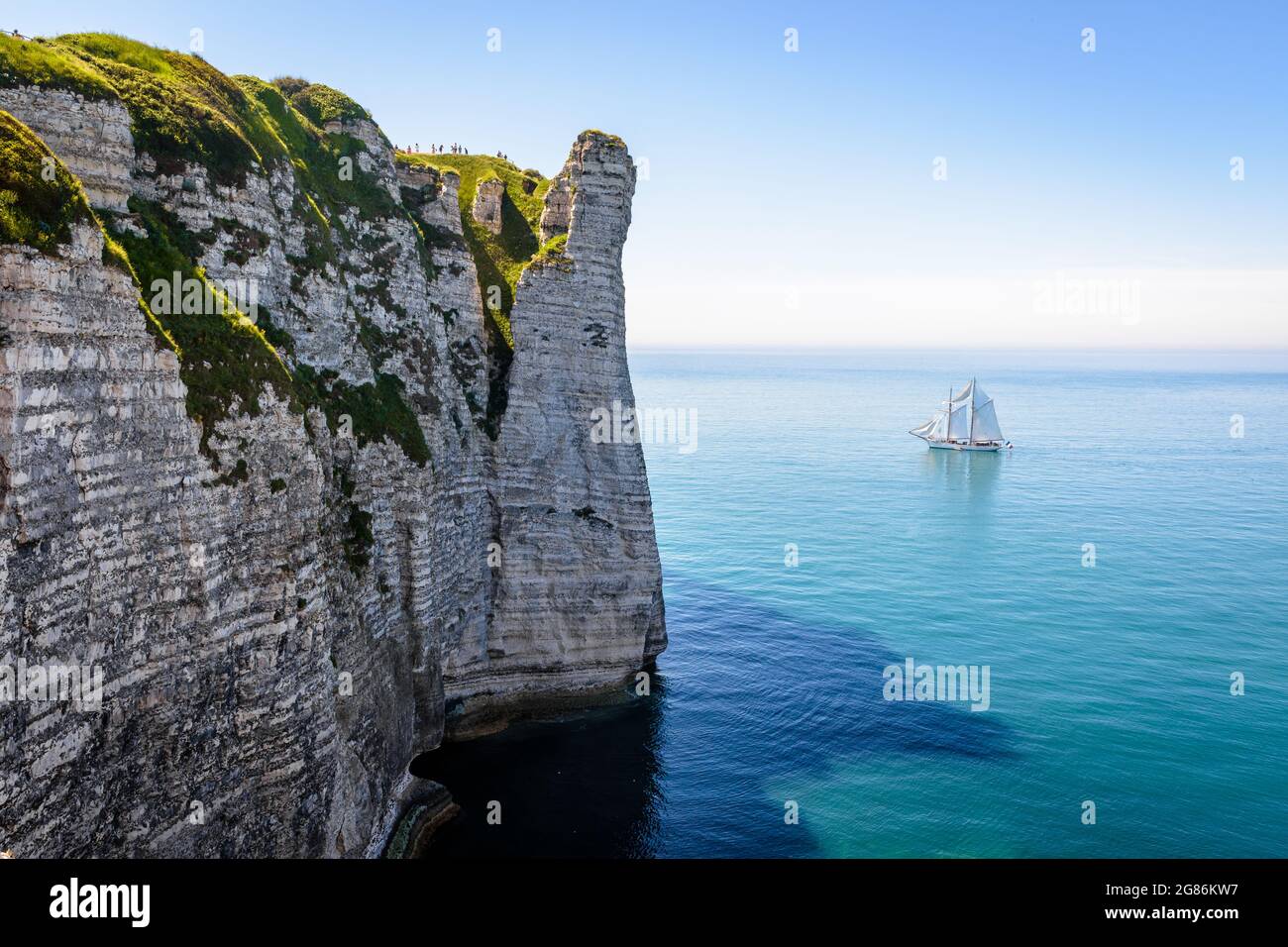 A white sailing ship is cruising, in full sail, off the Aval cliff in ...