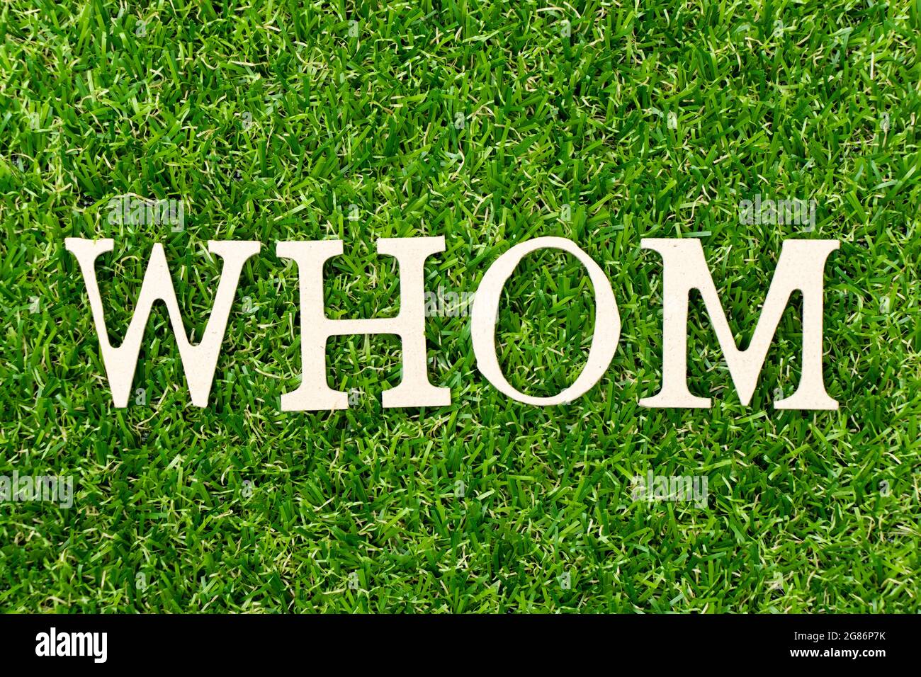 Wood letter in word whom on green grass background Stock Photo - Alamy