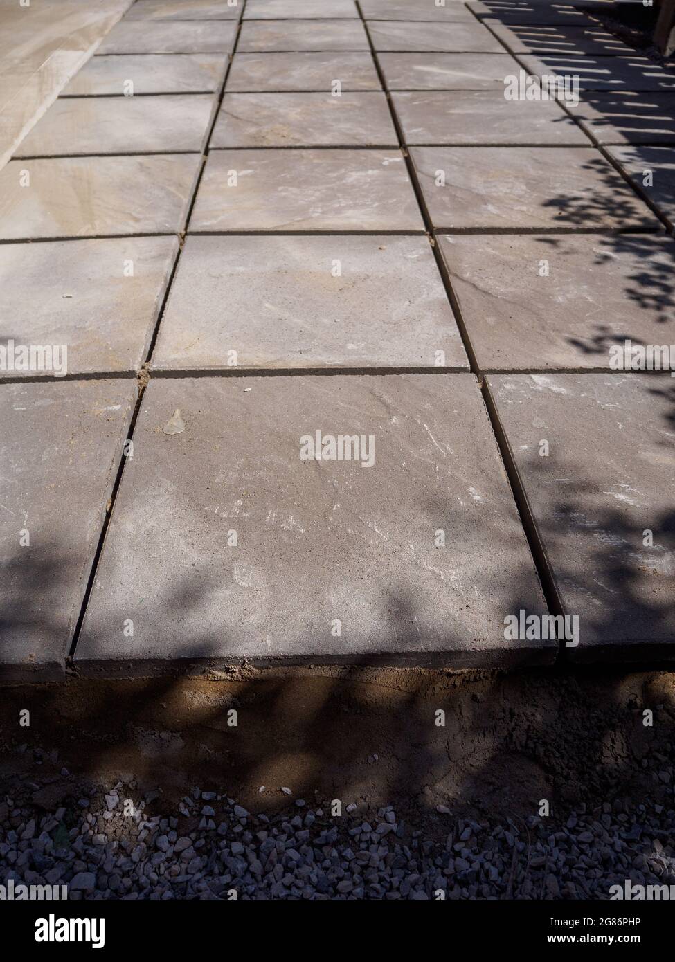 Laying patio slabs and landscaping a new outdoor floor in a garden ...