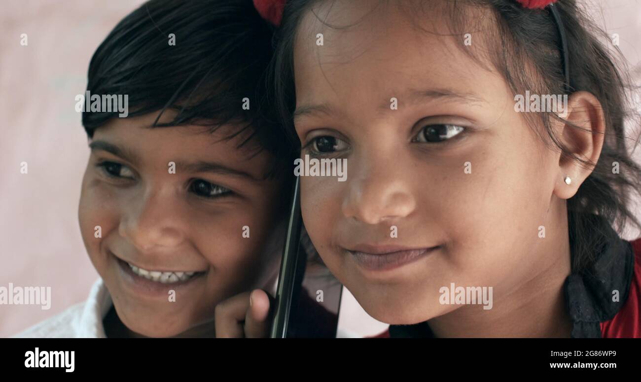 Pair of smiling South Asian children speaking on the phone Stock Photo ...