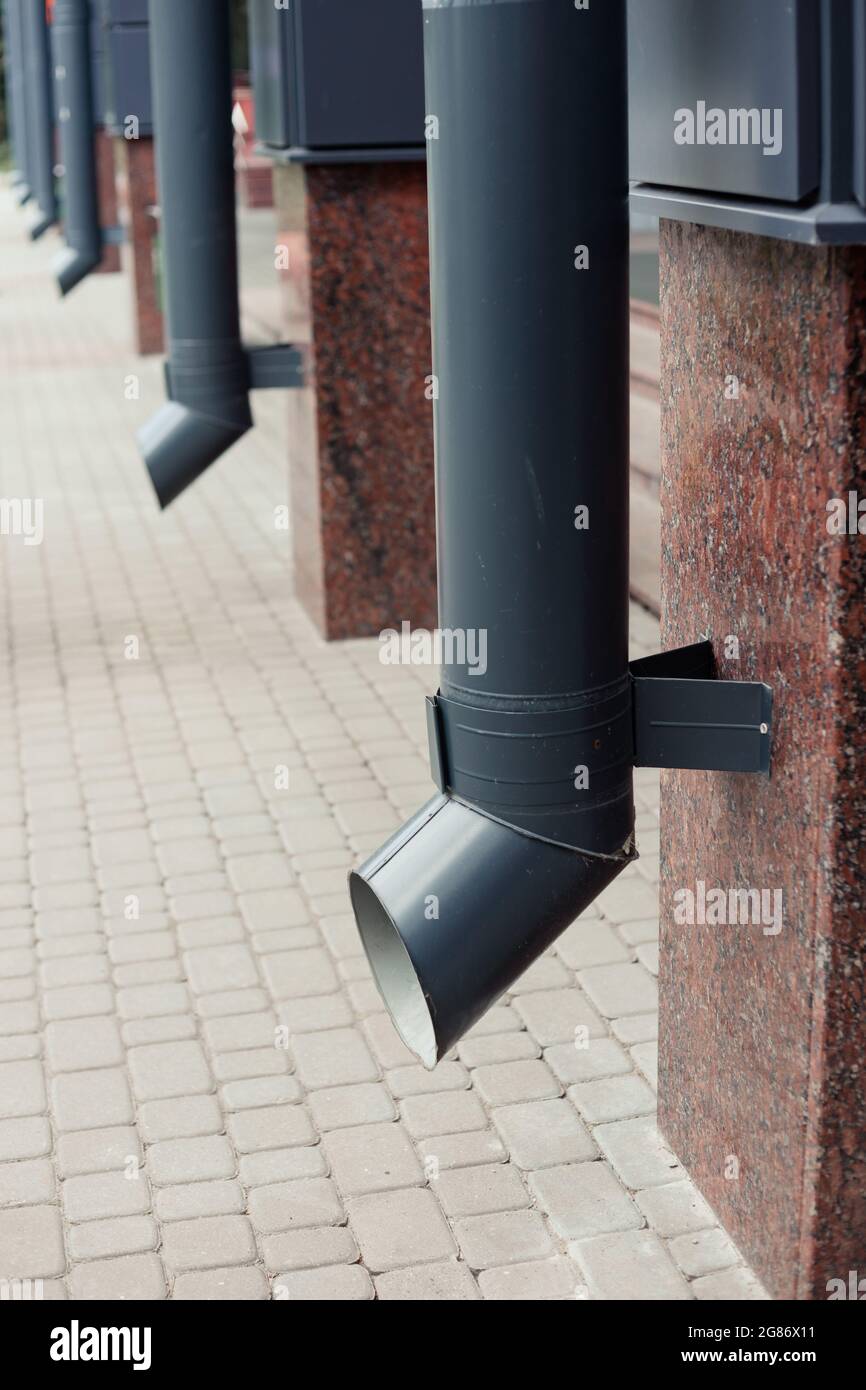 Stainless steel shiny downpipe at the corner of the house, close up ...
