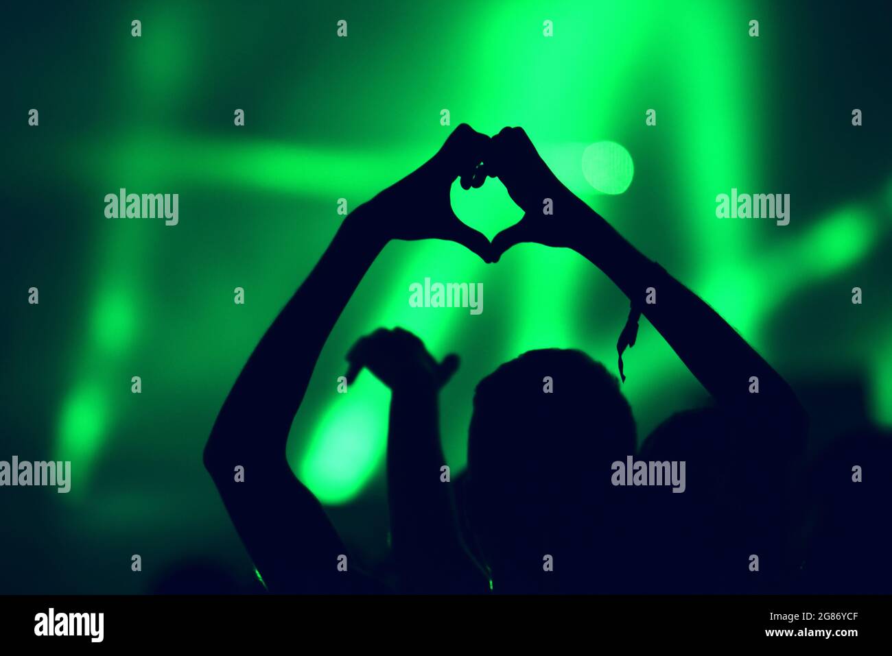 Silhouette of hands on a concert in front of bright stage lights doing ...