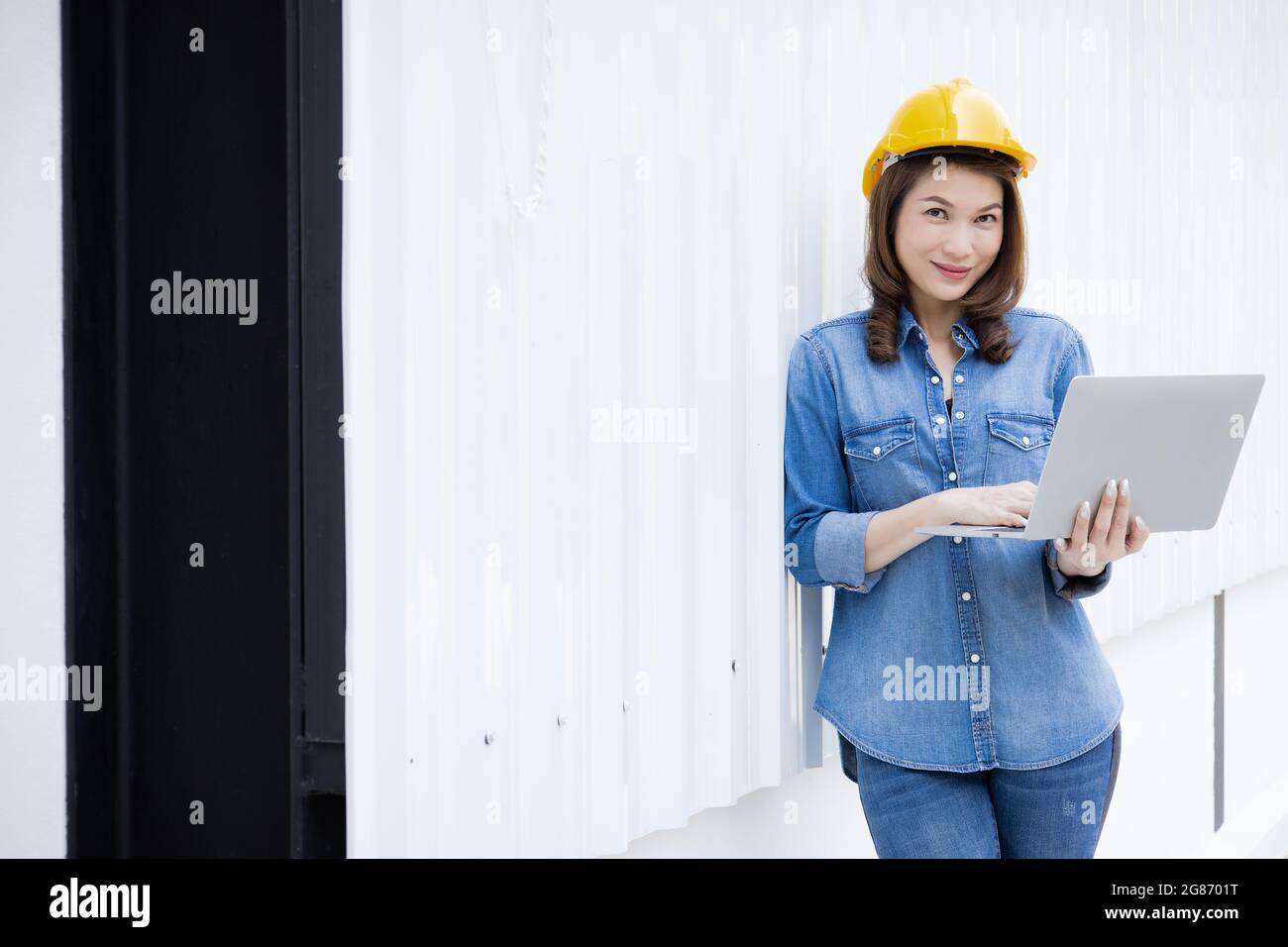 Beautiful Asian female engineer in jeans dress wearing yellow safety ...