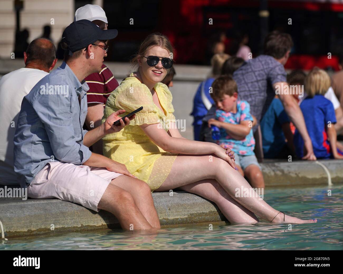People dipping their feet into the fountains in Trafalgar Square ...
