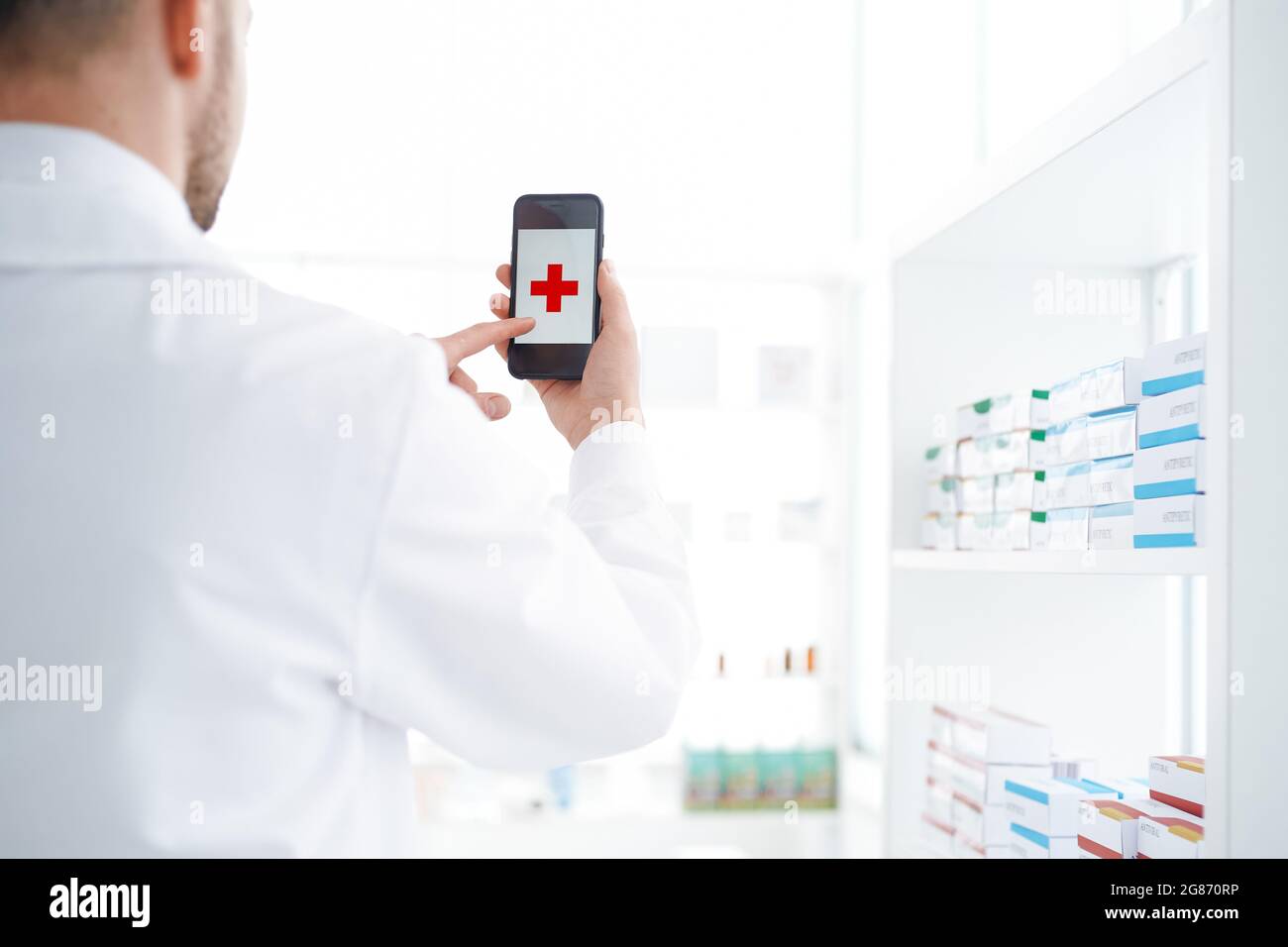 rear view . pharmacist using a smartphone in his pharmacy. photo with a ...