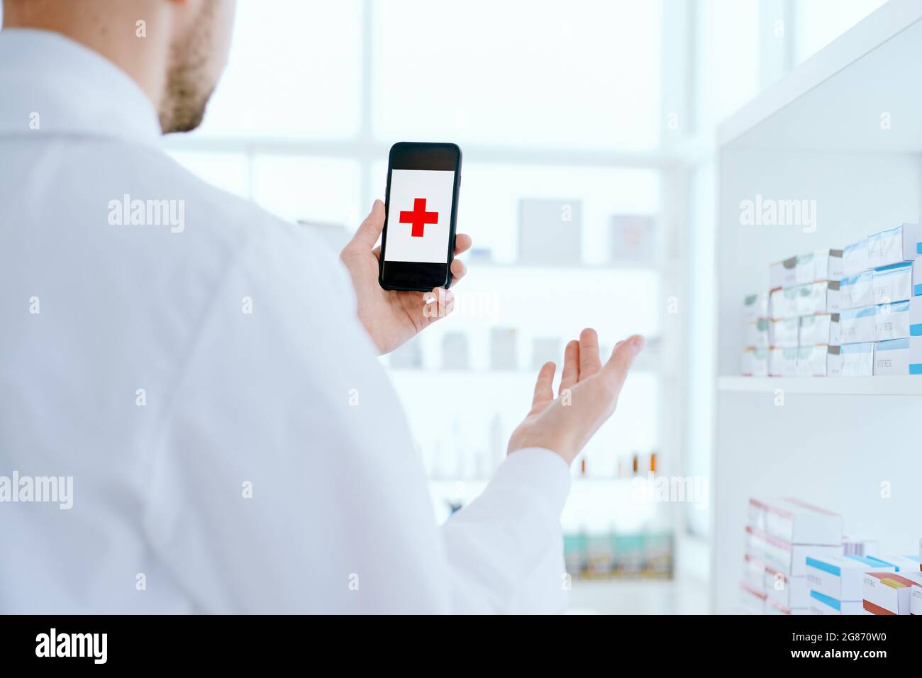 rear view . pharmacist with a smartphone standing near the shelf with ...