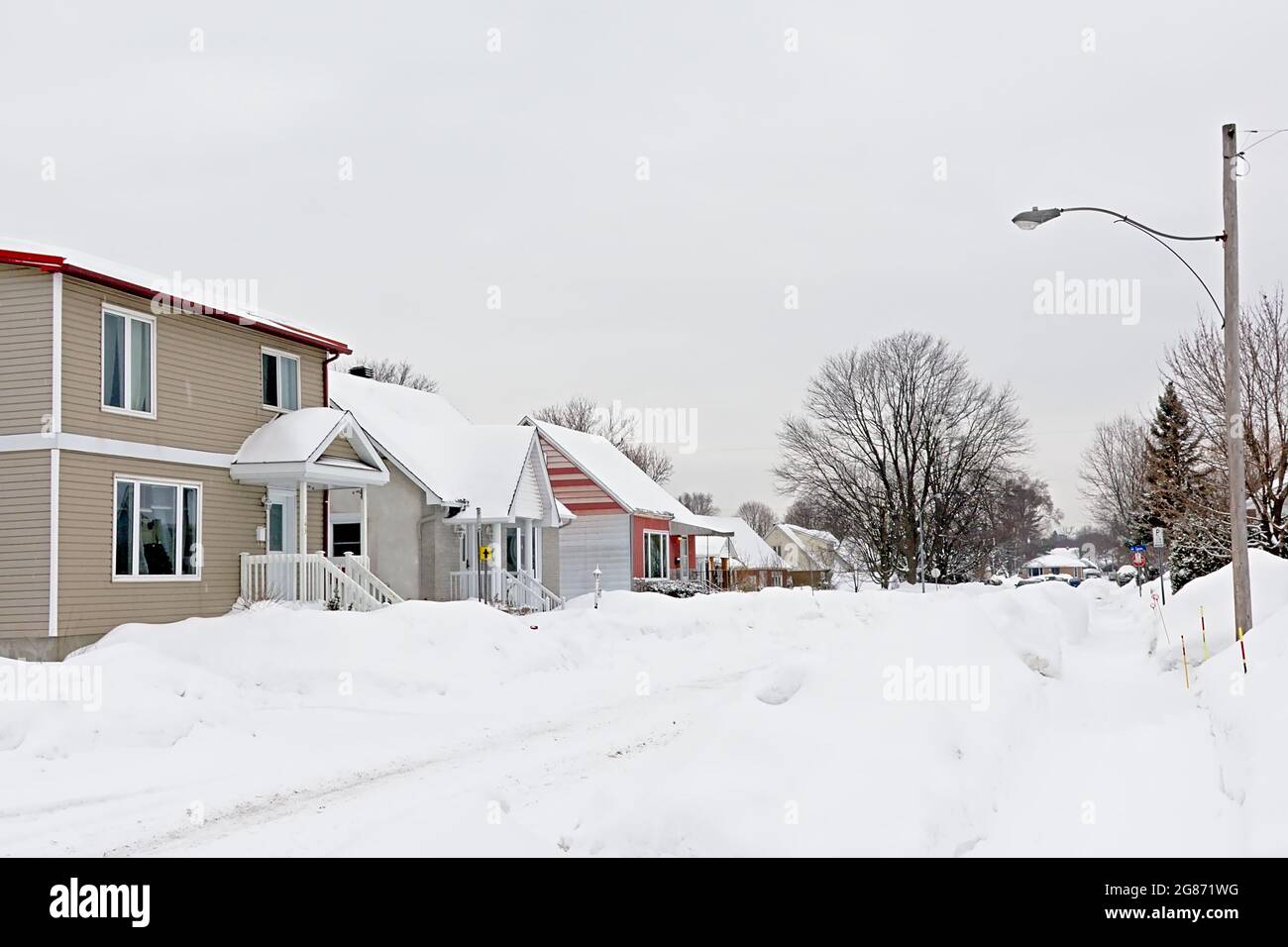 Typical canadian houses with big heaps of snow in front on a cold grey ...