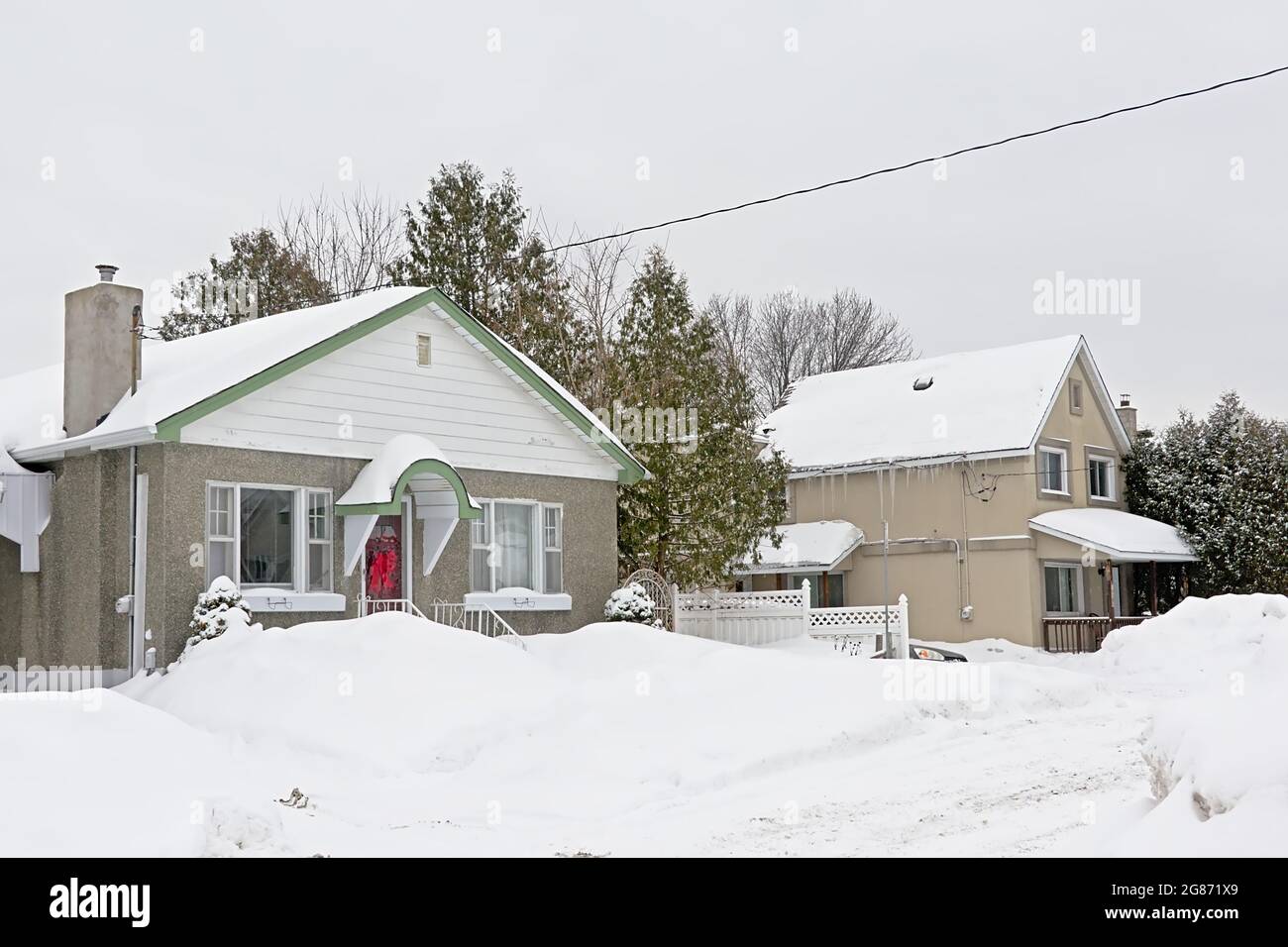 Typical canadian houses with big heaps of snow in front on a cold grey ...