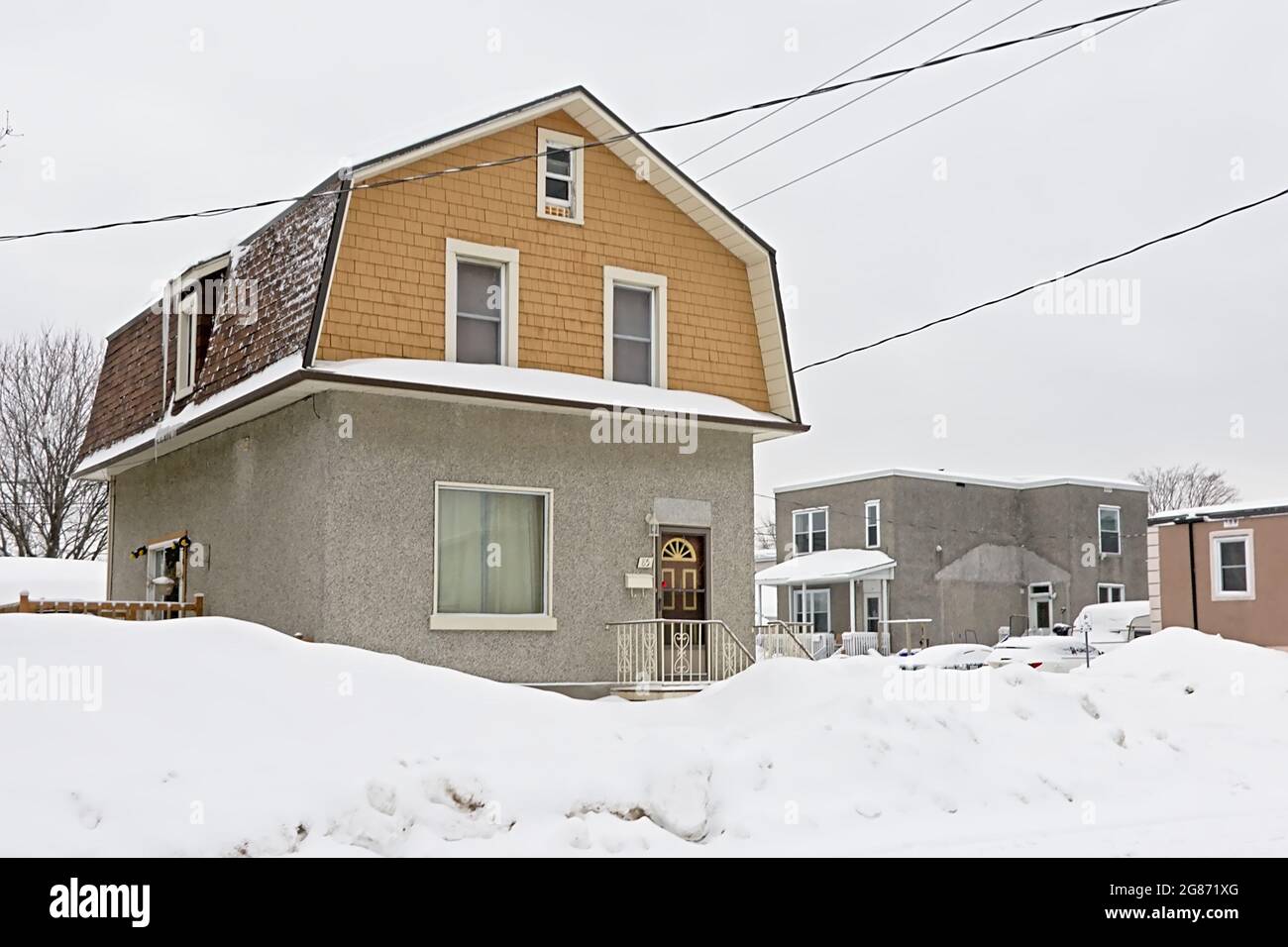 Typical canadian houses with big heaps of snow in front on a cold grey ...