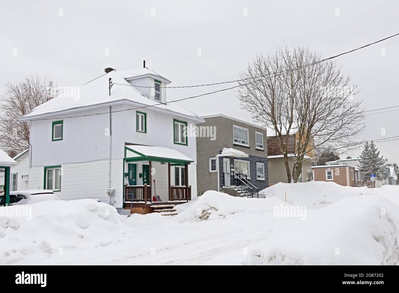Typical canadian houses with big heaps of snow in front on a cold grey ...