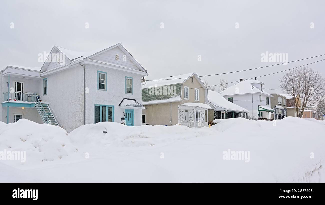 Typical canadian houses with big heaps of snow in front on a cold grey ...