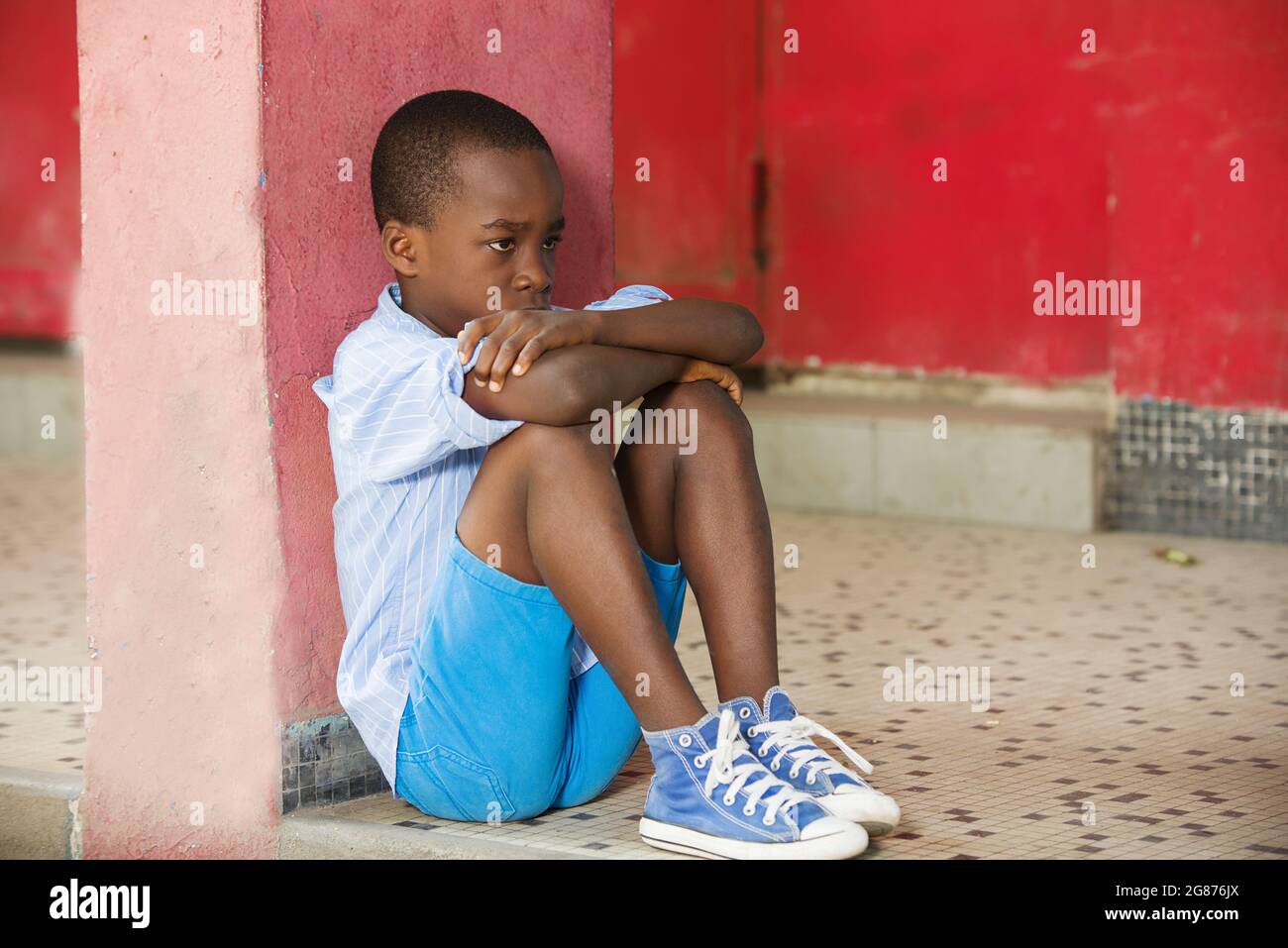 Composition of child abuse of a scared young boy sitting outside ...
