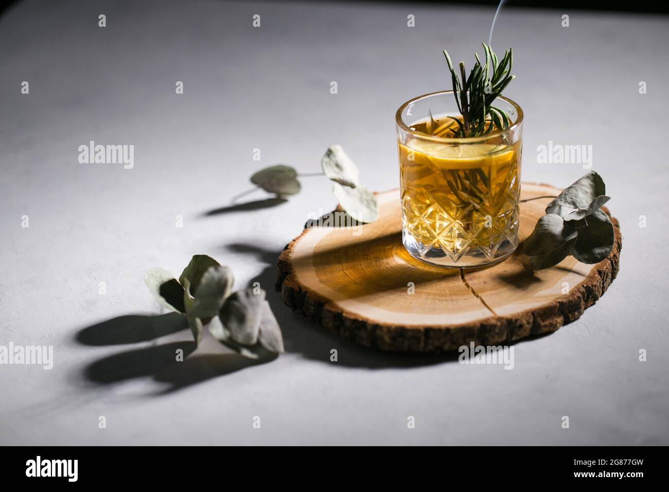 Yellow cocktail on the wooden podium eucalyptus rosemary dark moody ...