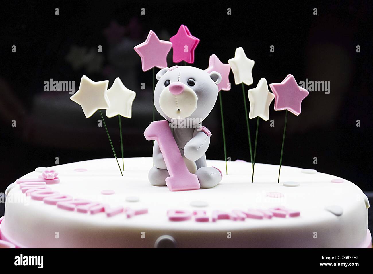Selective of a birthday cake with a teddy bear holding the number 1 ...