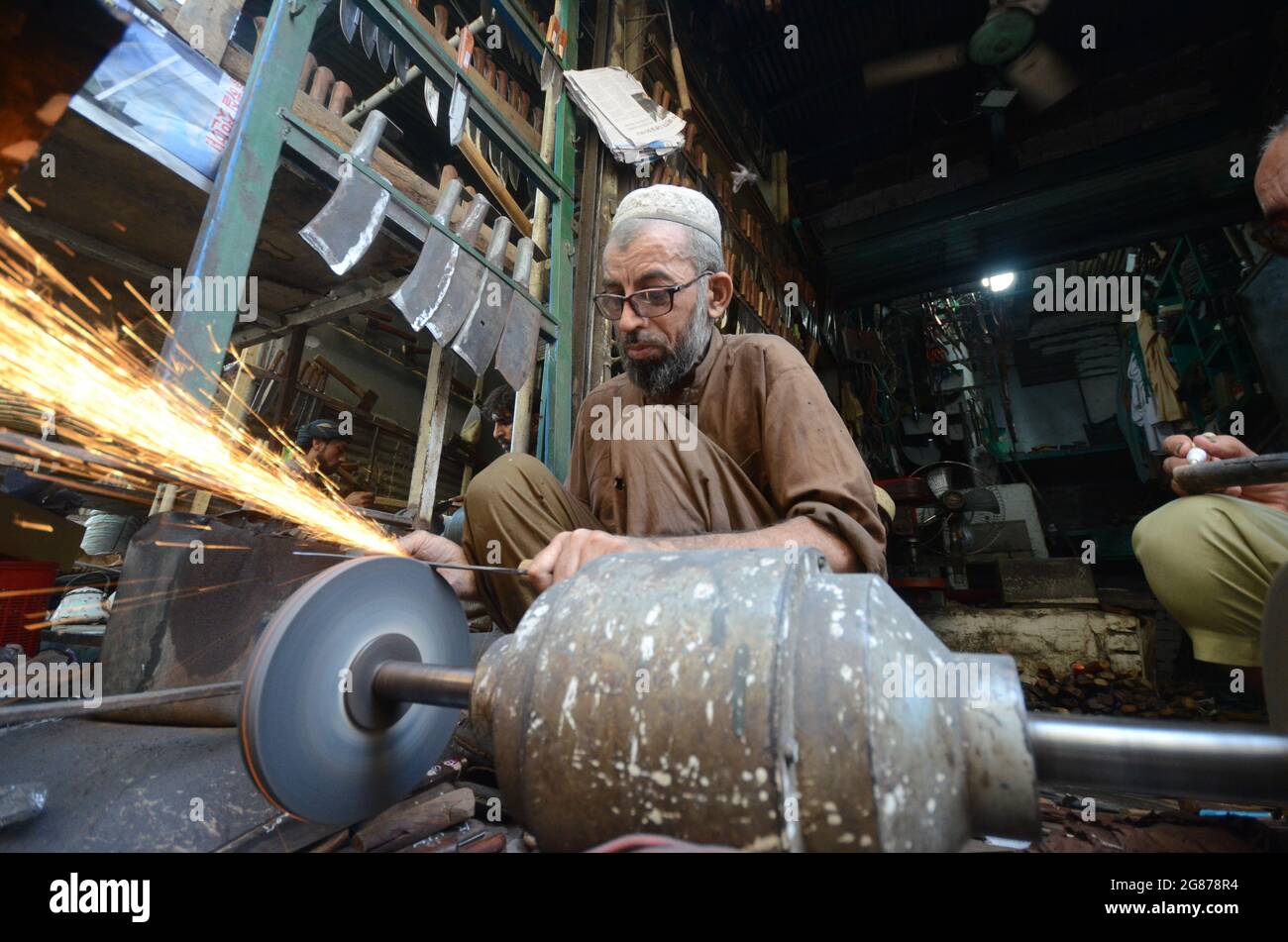Peshawar, Pakistan. 17th July, 2021. A Pakistani vendor sharpen axe ...