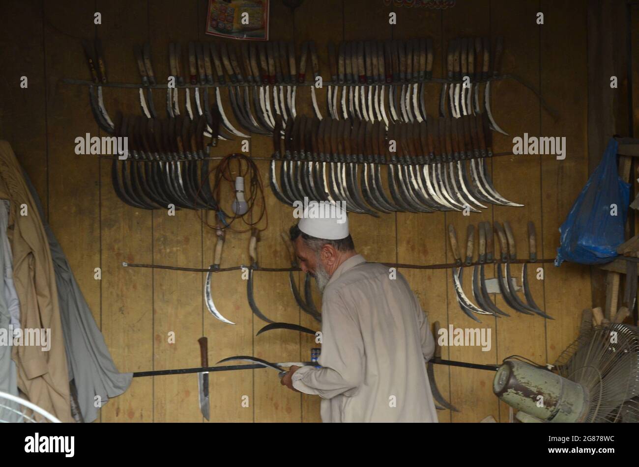 Peshawar, Pakistan. 17th July, 2021. A Pakistani vendor sharpen axe ...
