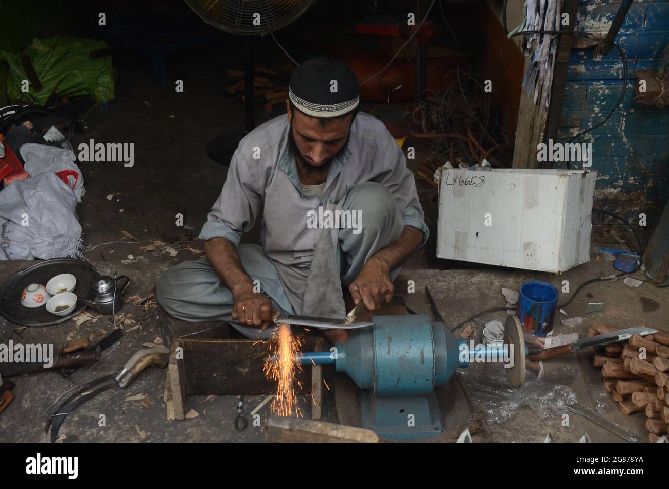 Peshawar, Pakistan. 17th July, 2021. A Pakistani vendor sharpen axe ...