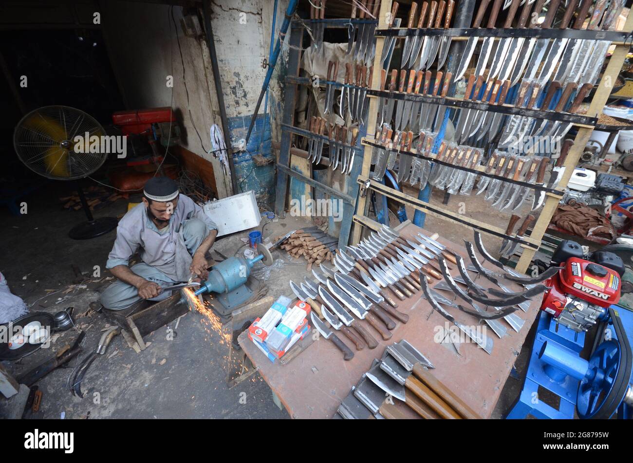 Peshawar, Pakistan. 17th July, 2021. A Pakistani vendor sharpen axe ...