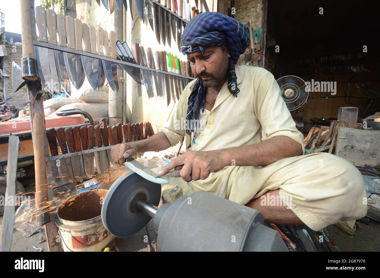 Peshawar, Pakistan. 17th July, 2021. A Pakistani vendor sharpen axe ...