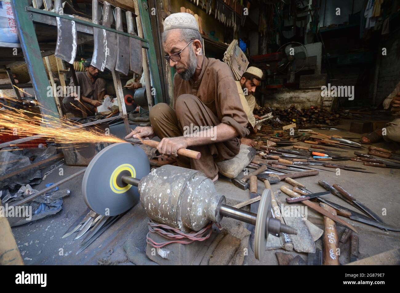 Peshawar, Pakistan. 17th July, 2021. A Pakistani vendor sharpen axe ...