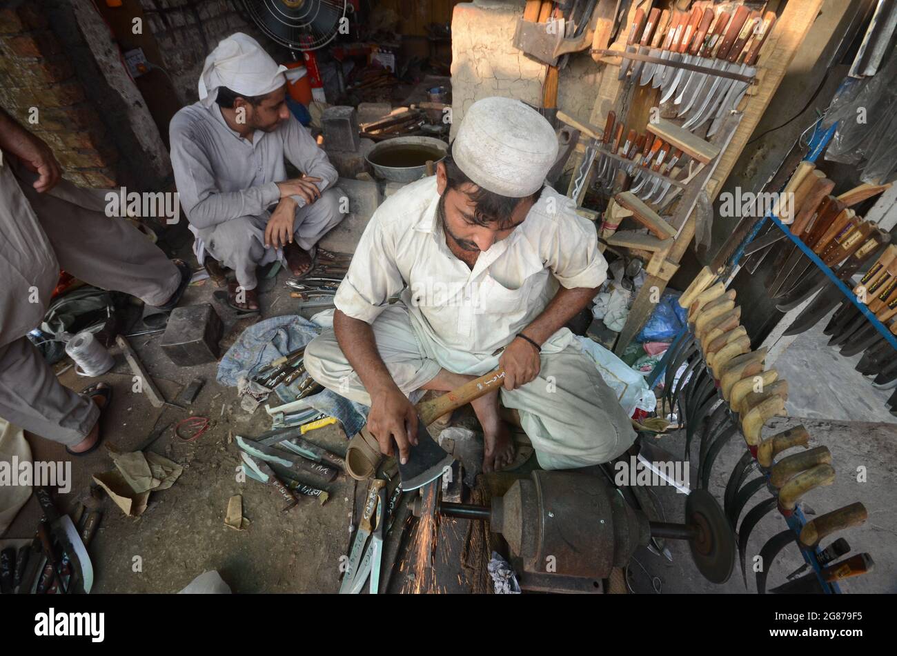 Peshawar, Pakistan. 17th July, 2021. A Pakistani vendor sharpen axe ...