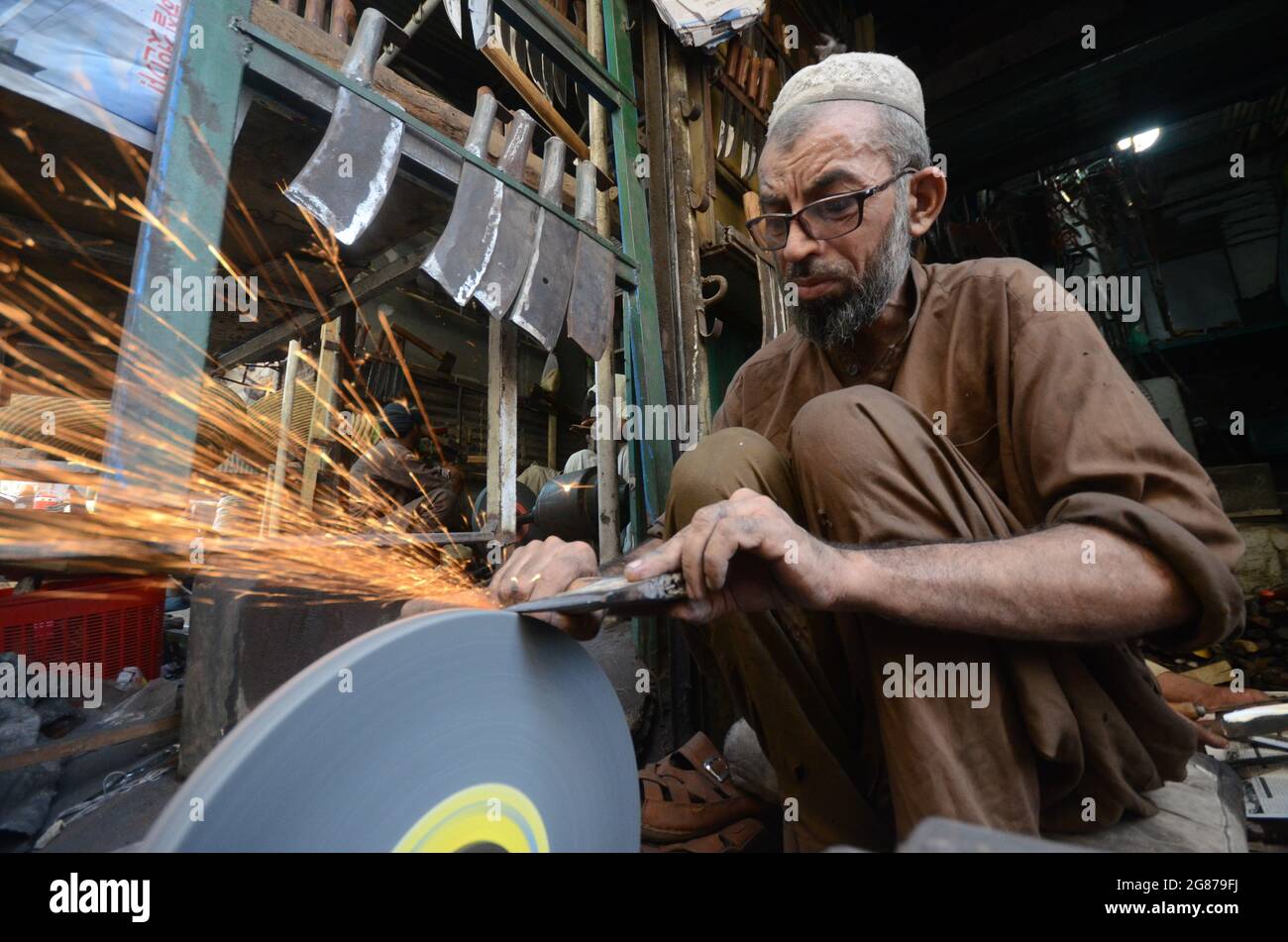 Peshawar, Pakistan. 17th July, 2021. A Pakistani vendor sharpen axe ...
