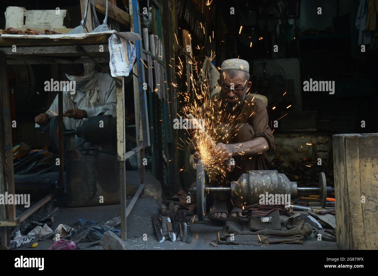 Peshawar, Pakistan. 17th July, 2021. A Pakistani vendor sharpen axe ...