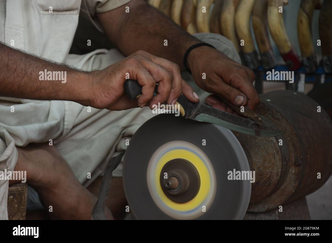 Peshawar, Pakistan. 17th July, 2021. A Pakistani vendor sharpen axe ...
