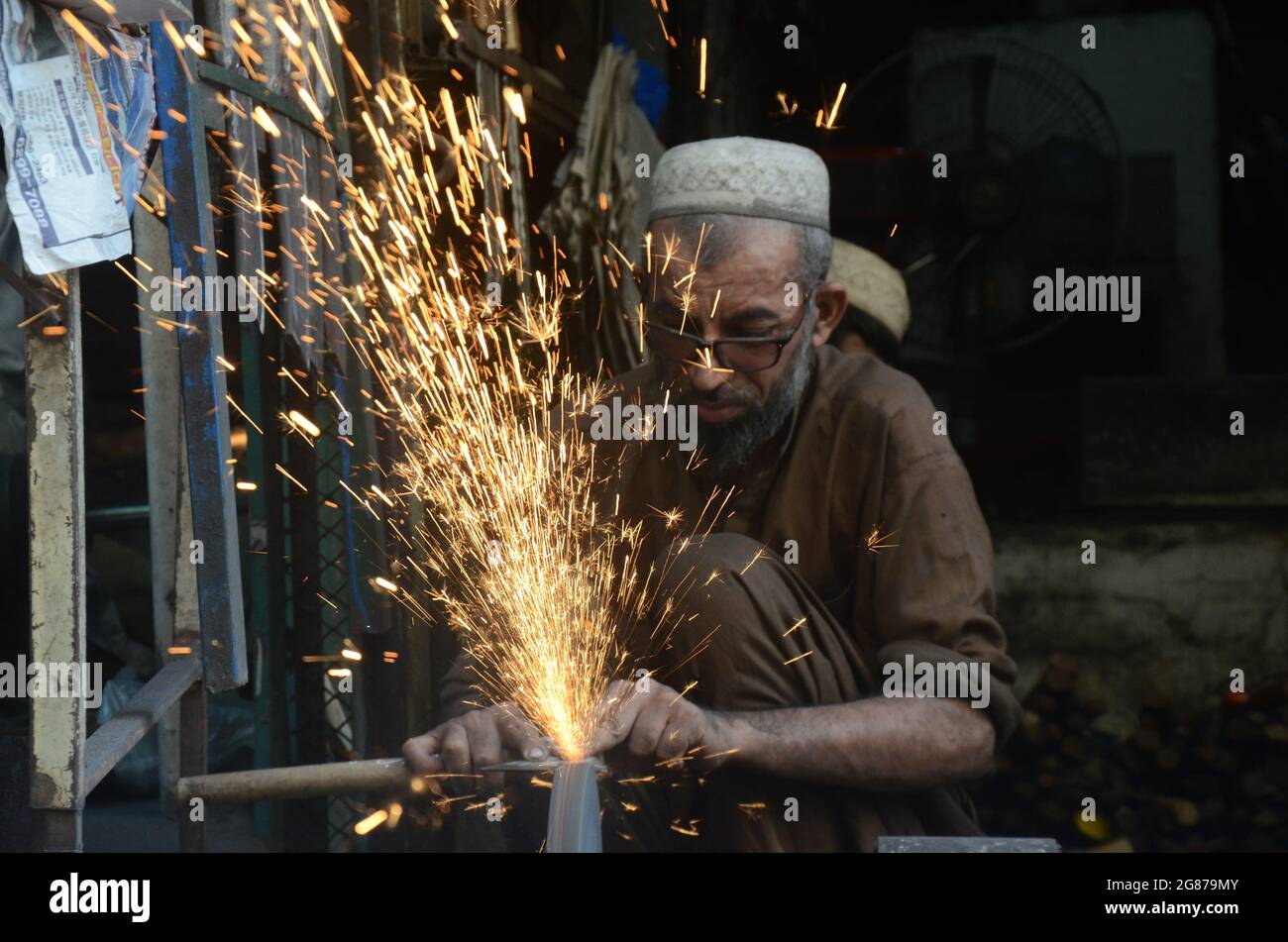 Peshawar, Pakistan. 17th July, 2021. A Pakistani vendor sharpen axe ...