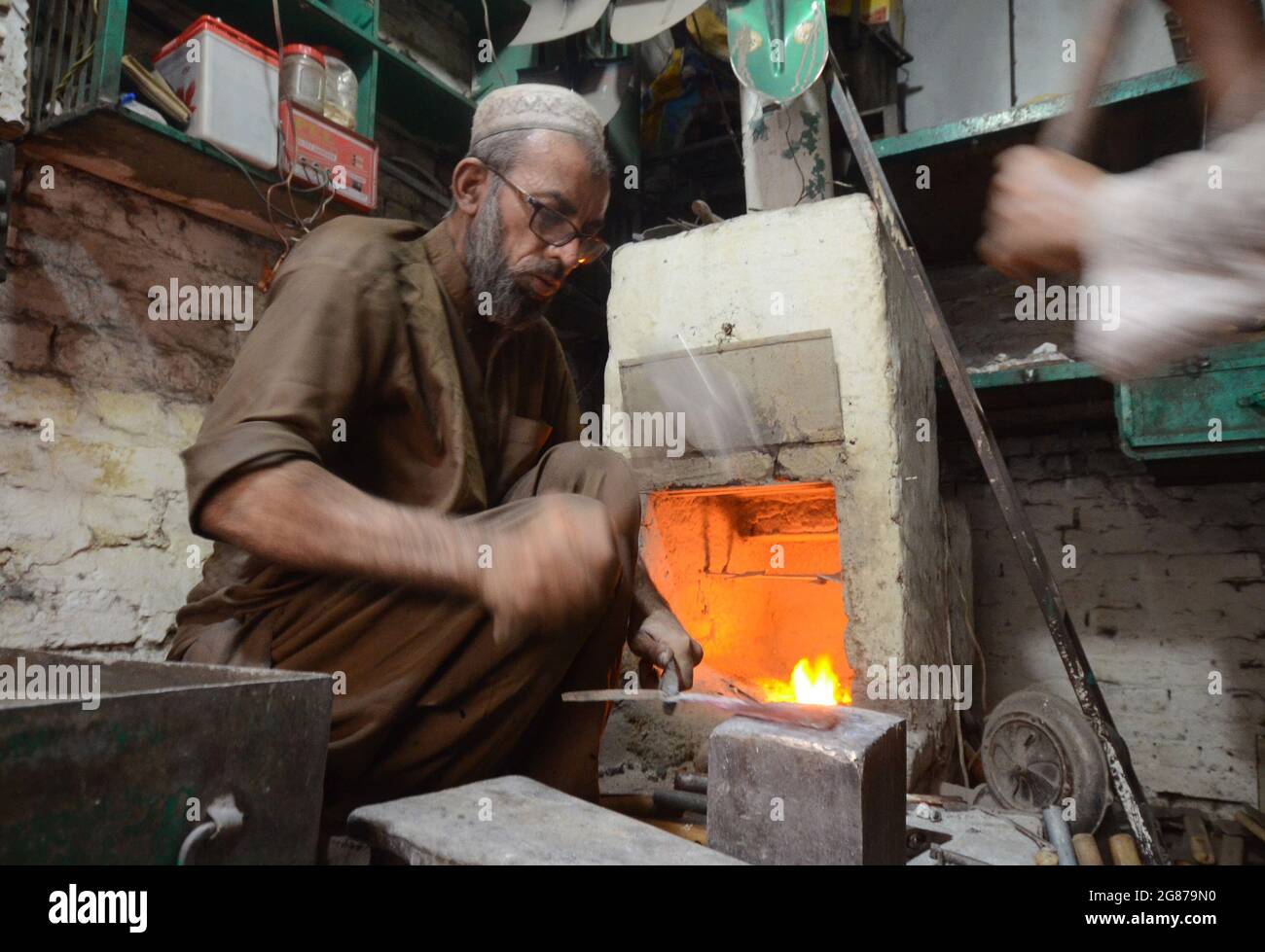Peshawar, Pakistan. 17th July, 2021. A Pakistani vendor sharpen axe ...